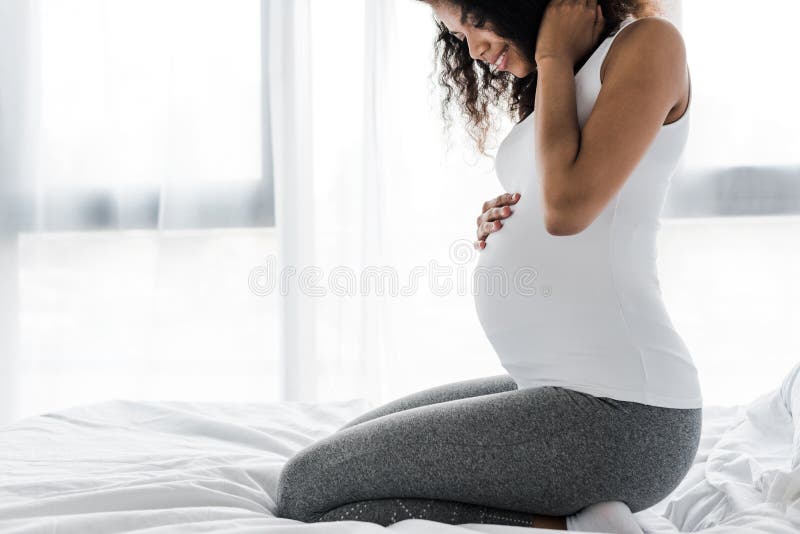 View Of Happy Curly Pregnant African American Woman Touching Belly
