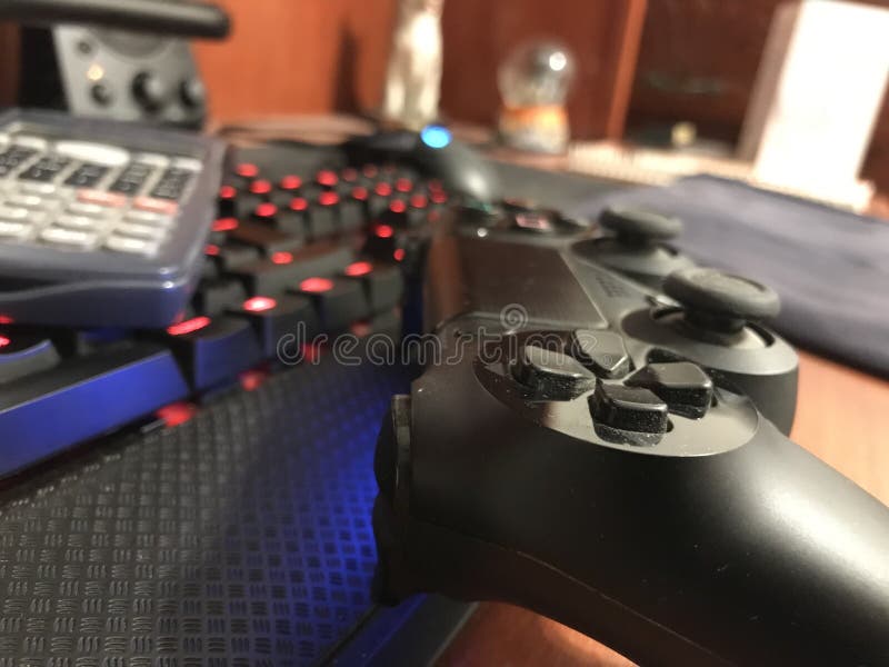 Modern Black Gaming Controller Over a Wooden Desk with a Mechanical ...