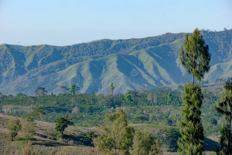View of Mountain Ridges and Sloping Hills with Trees Under a Clear Blue ...