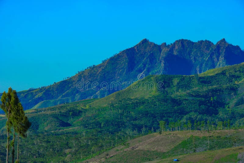 View of Mountain Ridges and Sloping Hills with Trees Under a Clear Blue ...
