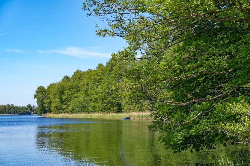 View Over a Lake To the Opposite Shore and a Small Boat Stock Photo ...
