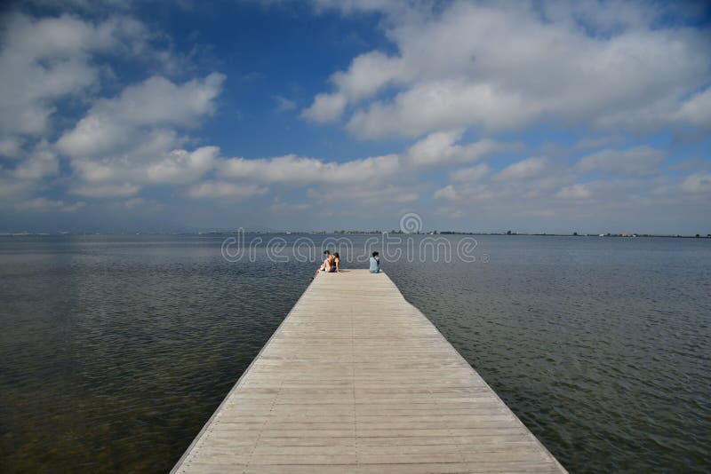 View of the Sea and People Sitting on the Dock. Stock Image - Image of ...