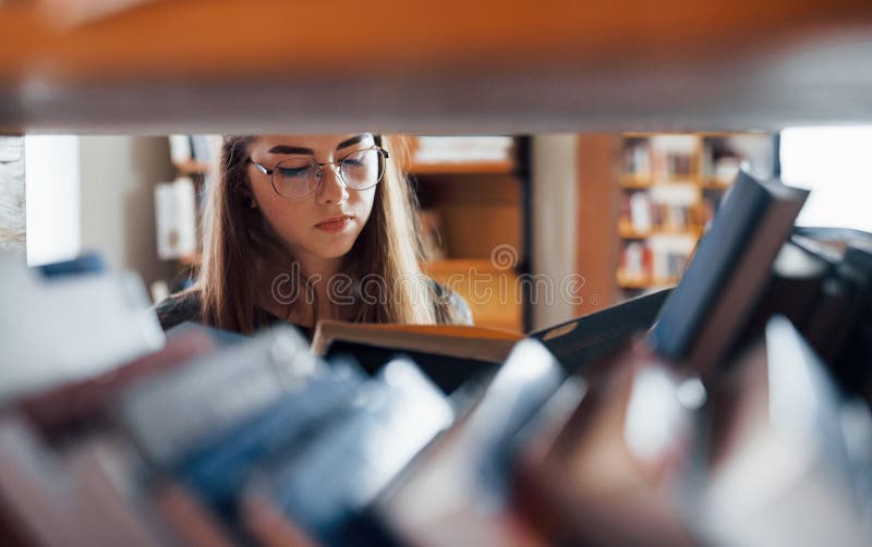 View through the Shelves. Female Student is in Library that Full of ...