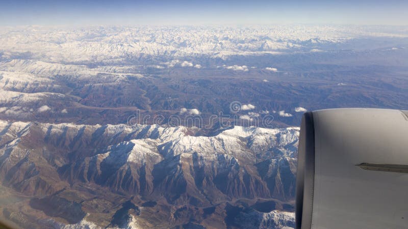 View of Sky, Snowy Mountains, and Airplane Engine through Window while ...