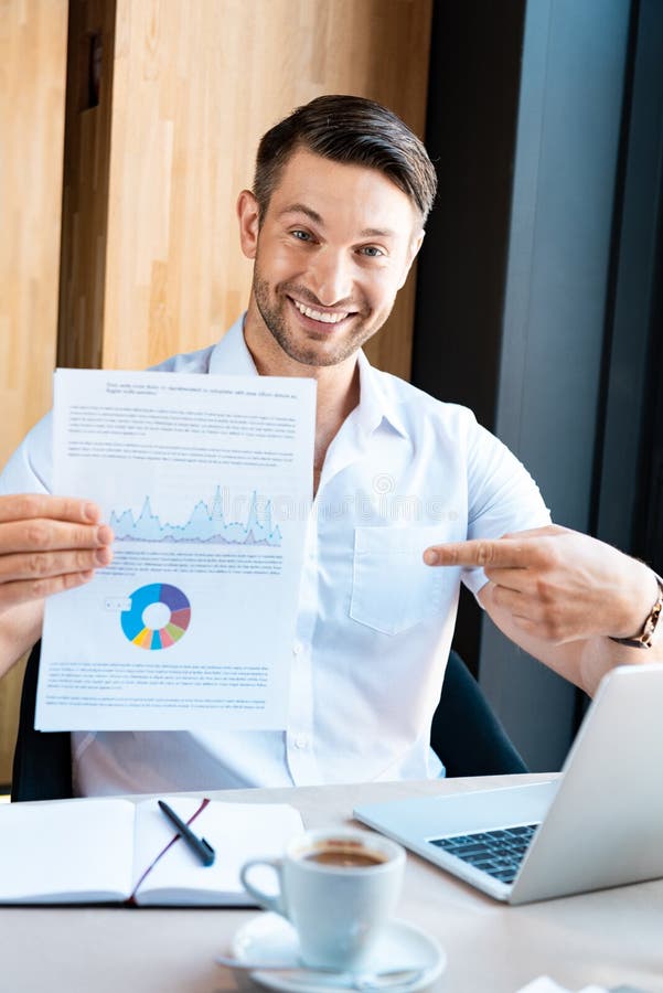 View of Smiling Man Pointing with Finger at Document with Diagram in ...
