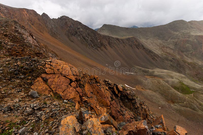View from a Steep Cliff and a Mountain Range with Clouds Above it ...