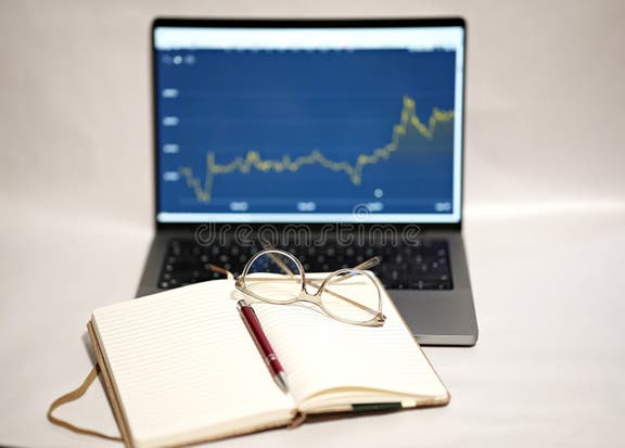 View Stock Marker Charts on a Laptop and Note Taking Notes in a Paper ...
