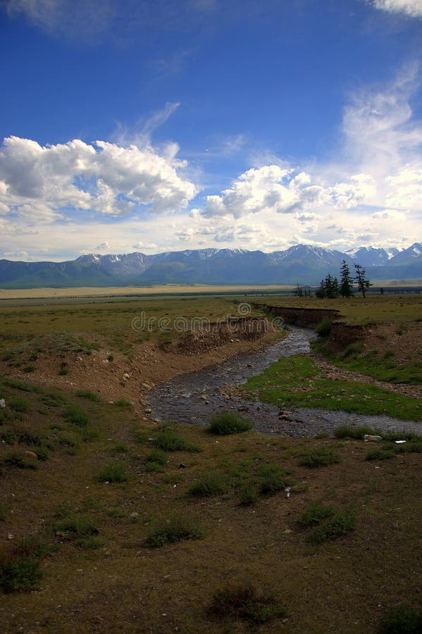 View of the Stream Flowing through the Steppe with Mountains Covered in ...