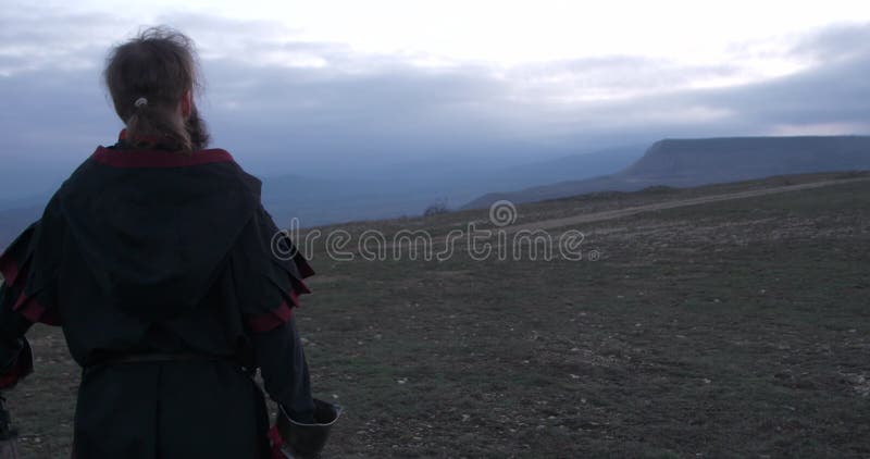 View To the Back of Knight that Stands with Sword and Looks To Horizon ...