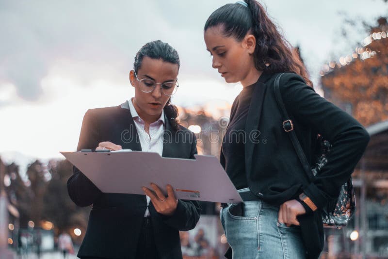 View of Two Female Students Checking on a Task while Standing Outdoors ...