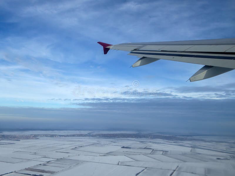 View of Wing from Plane Window, Flying Above Snowy Fields in Winter ...