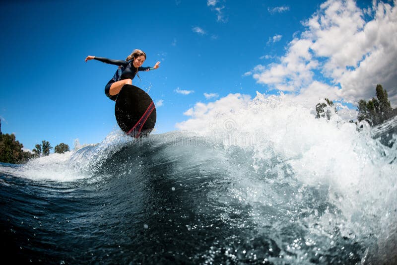 Energetic Young Woman Skillfully Jumping Over Splashing River Wave On