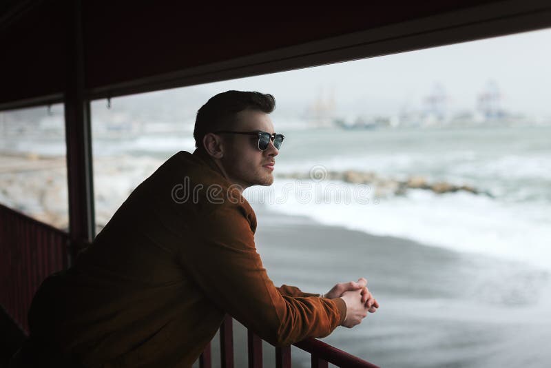 Young Man Leaning on the Railing in Front of the Beach Stock Image ...
