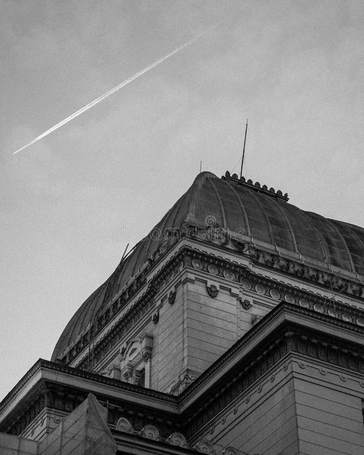 Vintage Building Facade with an Airplane Soaring through the Sky Above ...