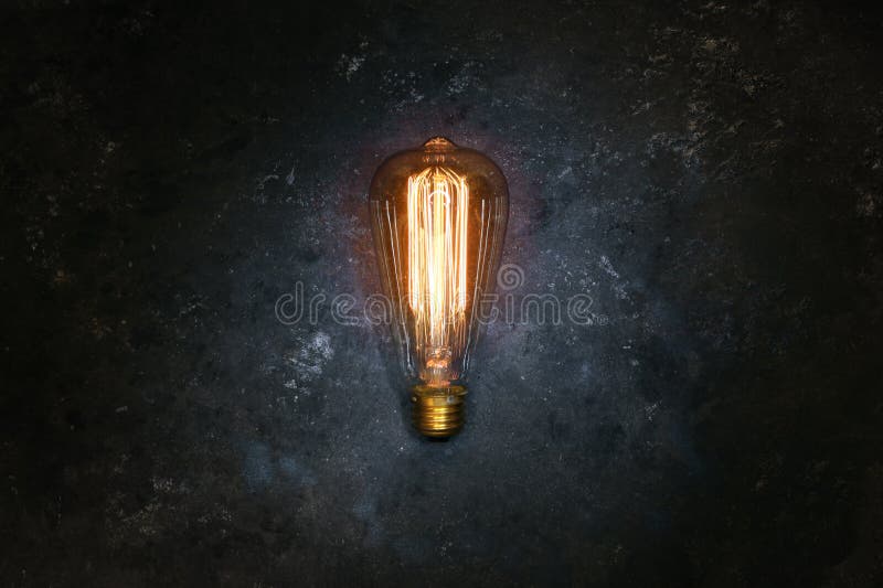 Vintage Old Light Bulb Glowing Yellow on Rough Dark Background. Idea ...