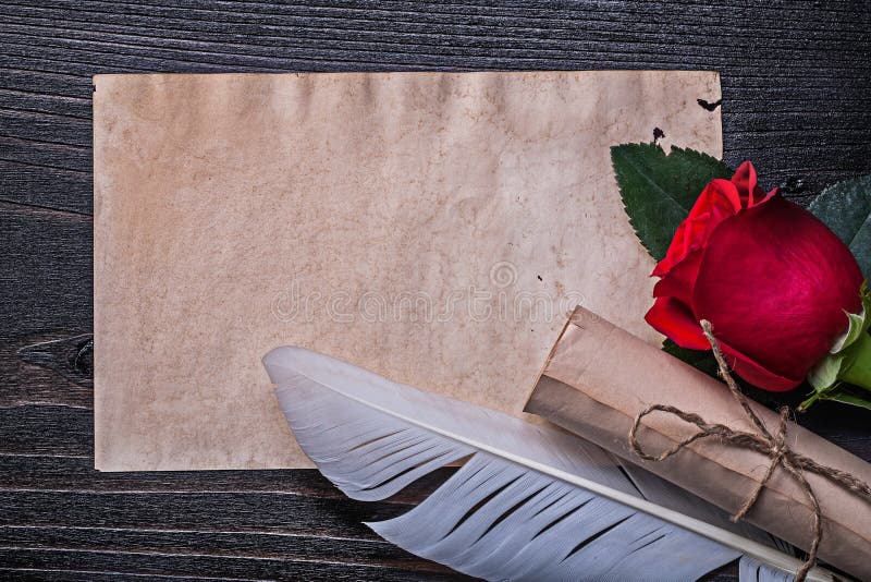 Vintage paper roll red rose feather on wooden - Stock Image - Everypixel