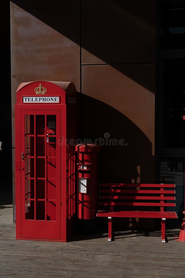 Vintage Red Phone Booth and a Wooden Bench Situated in Front of a Brick ...
