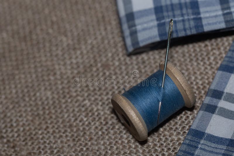 Vintage Wooden Spool with Blue Threads and Needle on a Textured ...