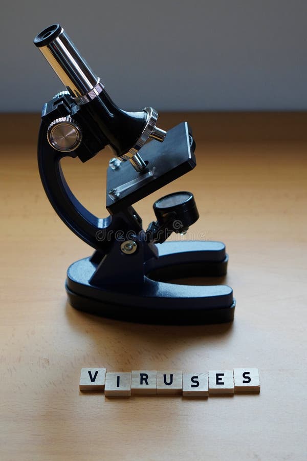 VIRUSES Concept. Wooden Letters with Microscope on a Light Wooden Table ...