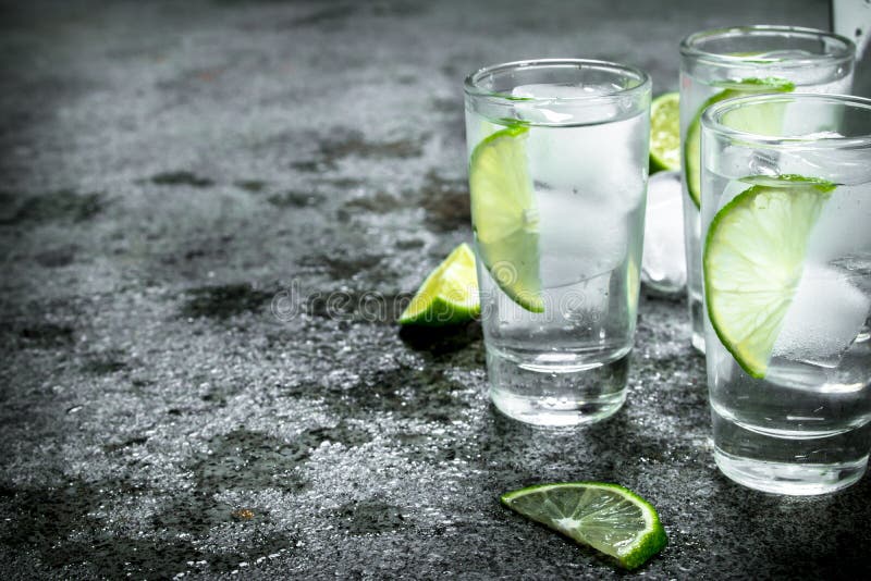 Vodka with Pieces of Lime and Ice Cubes. Stock Image - Image of black ...