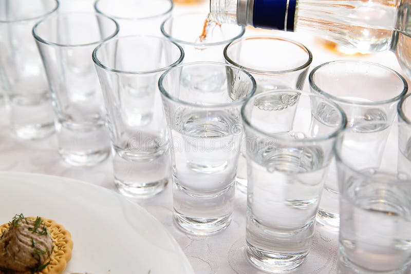 Vodka Pours from a Bottle in a Shot Standing on the White Table Stock ...