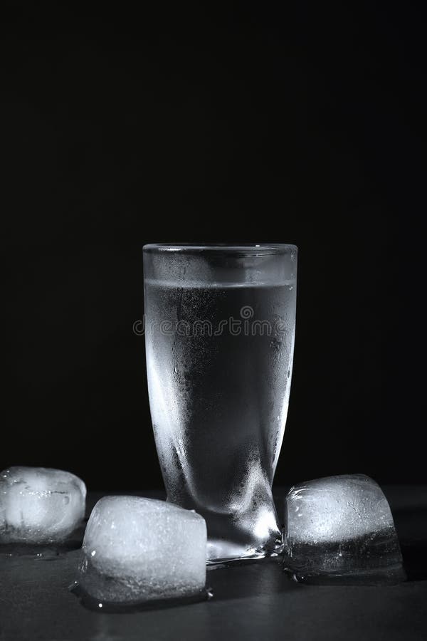 Vodka in Shot Glass with Ice on Table Against Black Background Stock ...