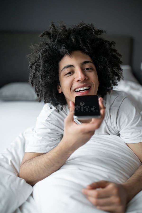 Young Man Lying in Bed and Recording a Voice Message Stock Image ...