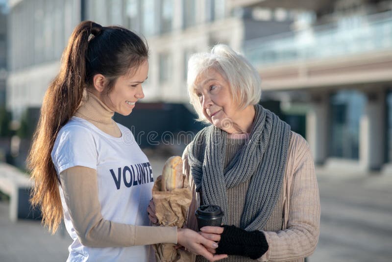 Volunteer Supporting Poor Woman while Bringing Bread and Tea Stock ...