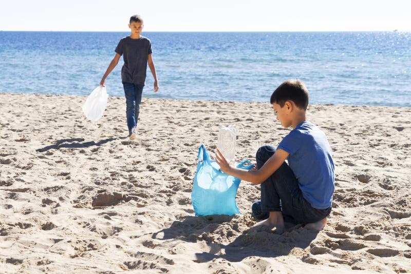 Volunteers Cleaning Beach from Plastic. Boys Walking on the Beach and ... Volunteers Cleaning Beach from Plastic. Boys Walking on the Beach and ...