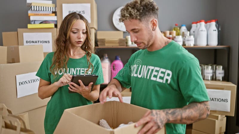 Volunteers, Man and Woman, Work Indoors Managing Donations, with One ...