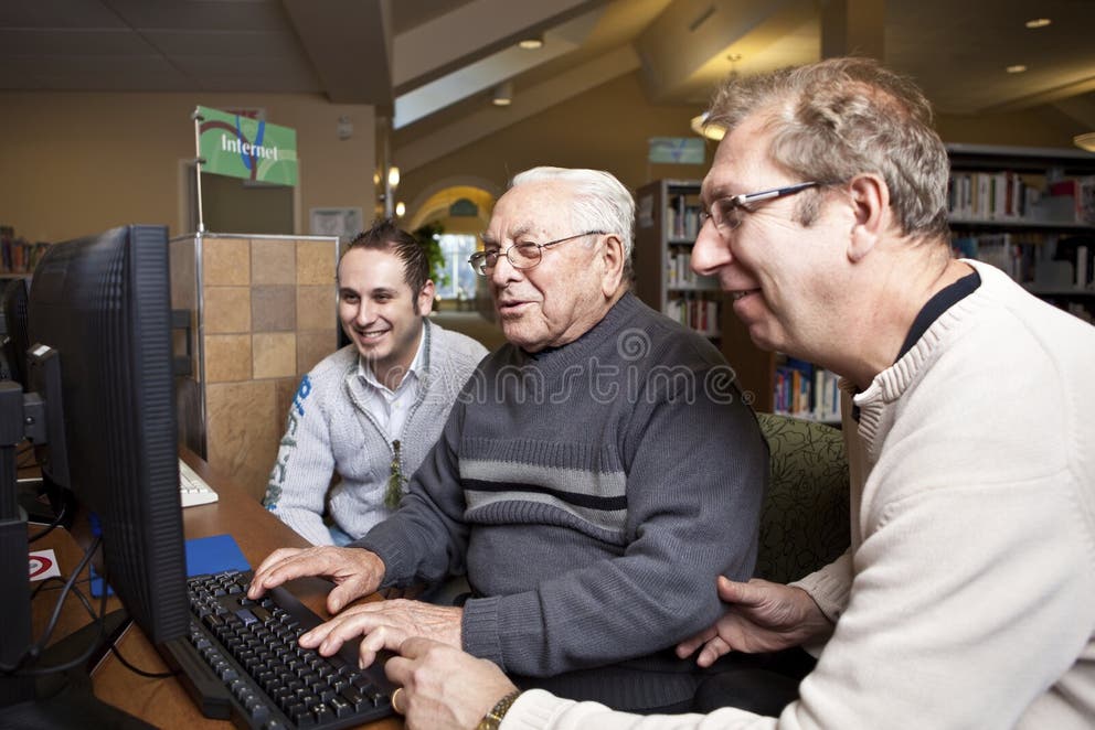 Volunteers Teaching a Senior How To Use a Computer Stock Photo - Image ...