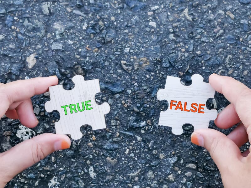 Hand Holding Jigsaw Puzzle Pieces Written True and False with Asphalt ...