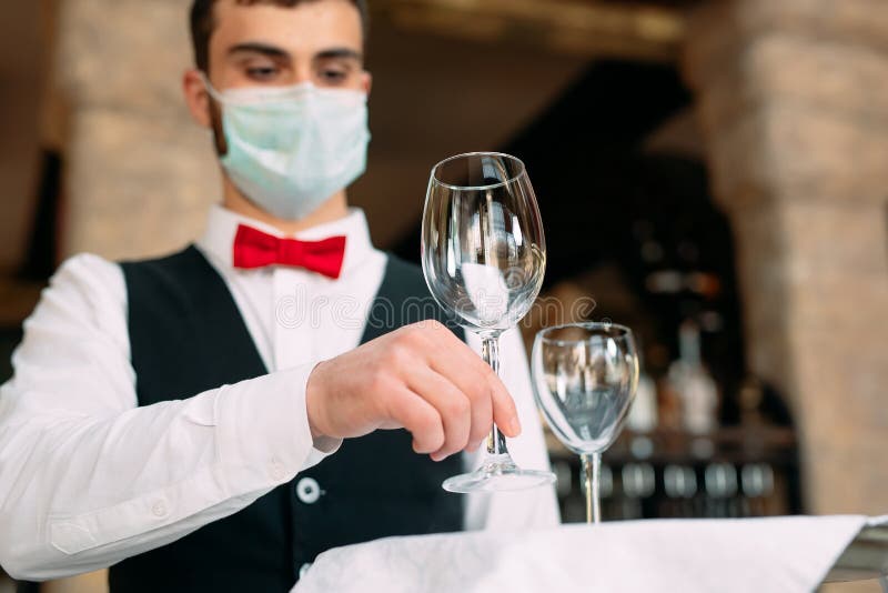 A Waiter in a Medical Protective Mask Serves the Table in the ...