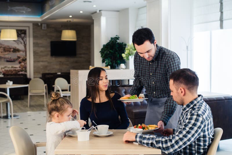 Waiter Serving Family in a Restaurant and Bringing Full Plate Stock ...