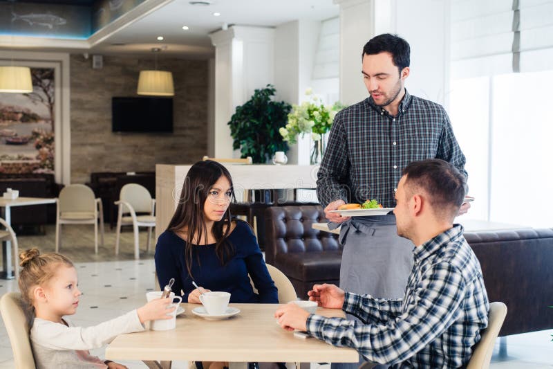 Waiter Serving Family in a Restaurant and Bringing Full Plate Stock ...