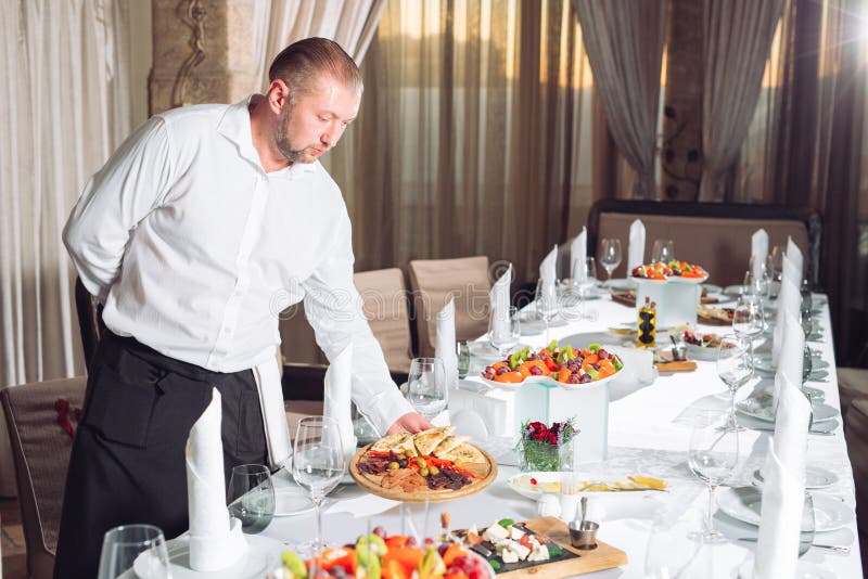 Waiter Serving Table in the Restaurant Preparing To Receive Guests ...