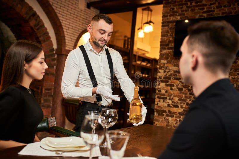 The Waiter in Uniform Offers Visitors Wine in Restaurant Stock Image ...