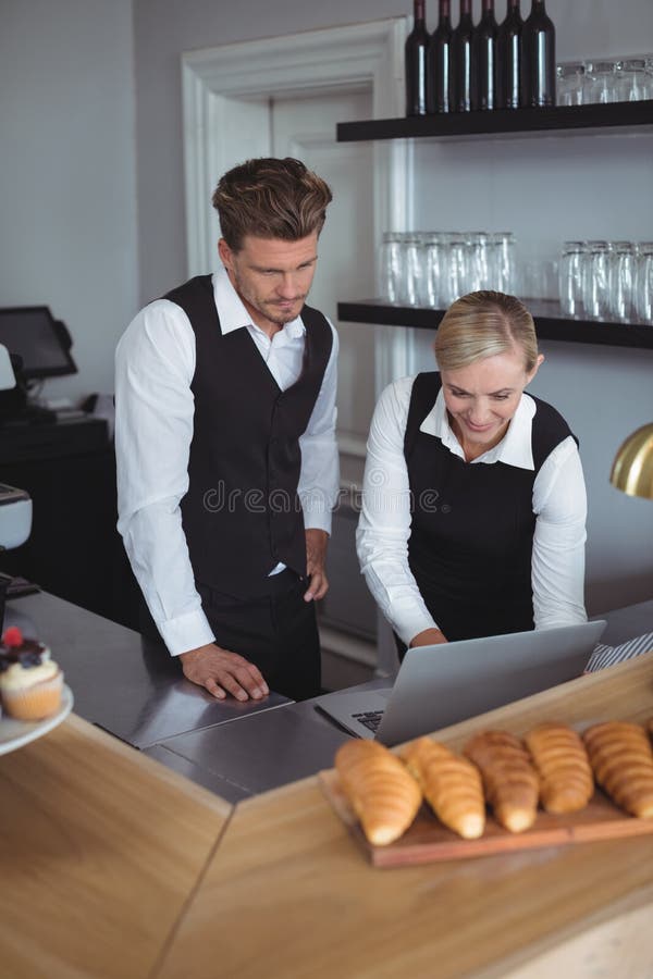 Waitress Using Digital Tablet while Waiter Preparing Coffee in ...