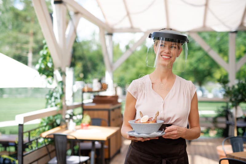 Waitress with Protective Face Shield Serving Customers Outdoors on ...