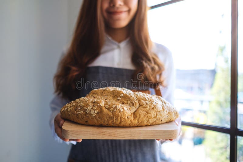 A Waitress Serving a Loaf of Whole Grain Bread Stock Photo - Image of ...