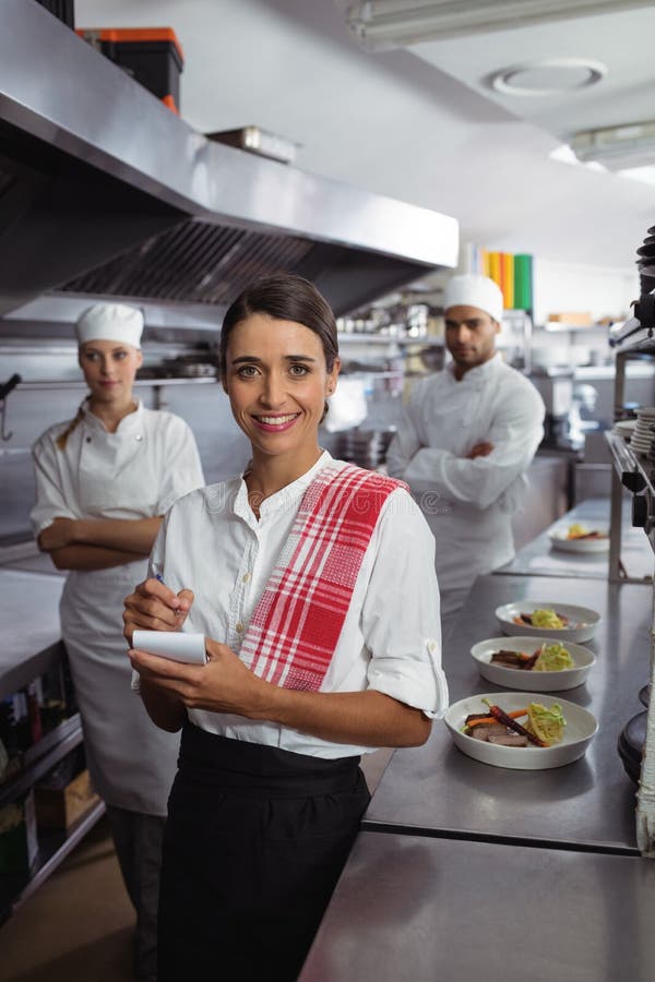 Waitress Standing with Kitchen Staff in Commercial Kitchen Stock Photo ...