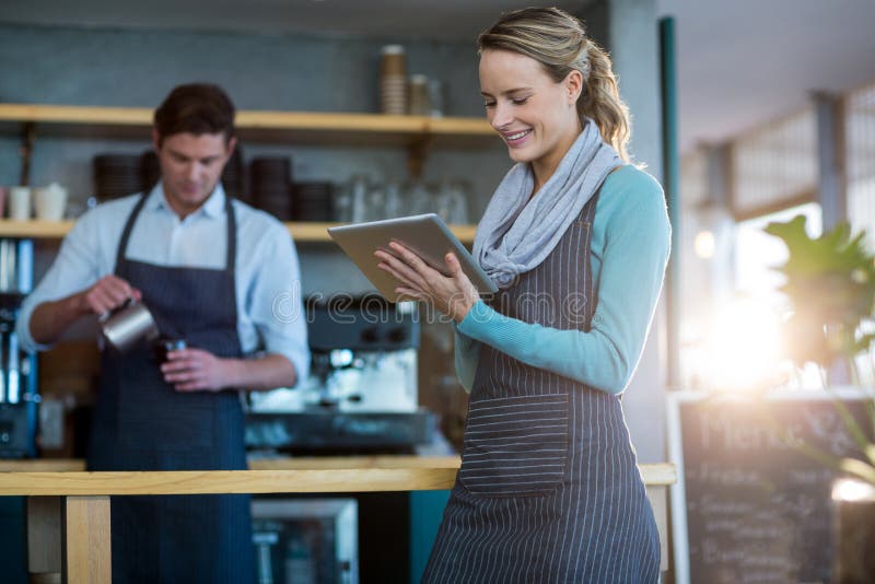 Waitress Using Digital Tablet while Waiter Preparing Coffee in ...
