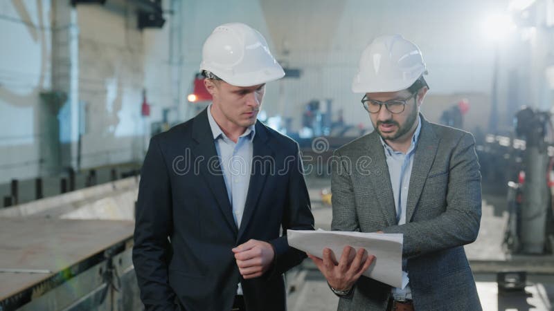Walking in Front of the Camera in Manufacturing Factory Two Engineers ...