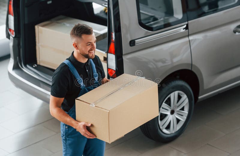 Walking and Holding Box in Hands. Delivery Man in Uniform is Indoors ...