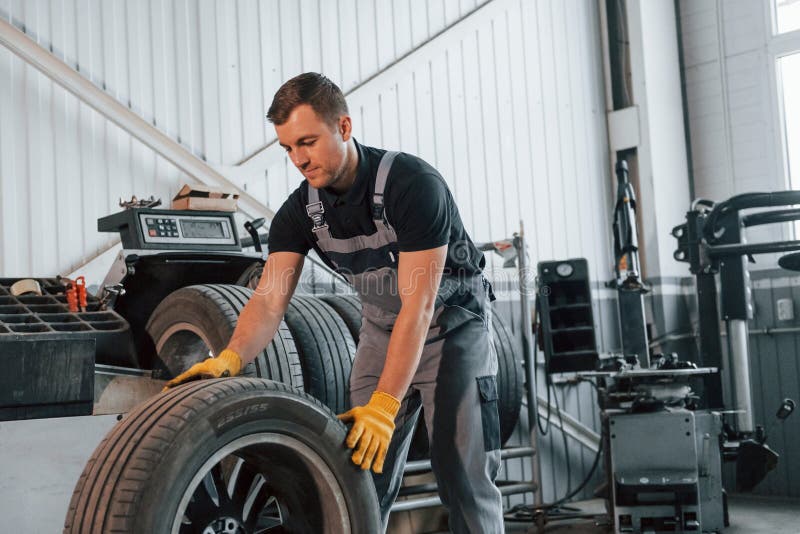 Walking with Tyre. Man in Uniform is Working in the Auto Service Stock ...