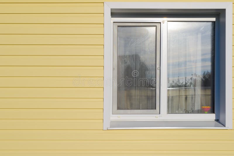 Wall of the House is Covered with Yellow Vinyl Siding and a Plastic ...