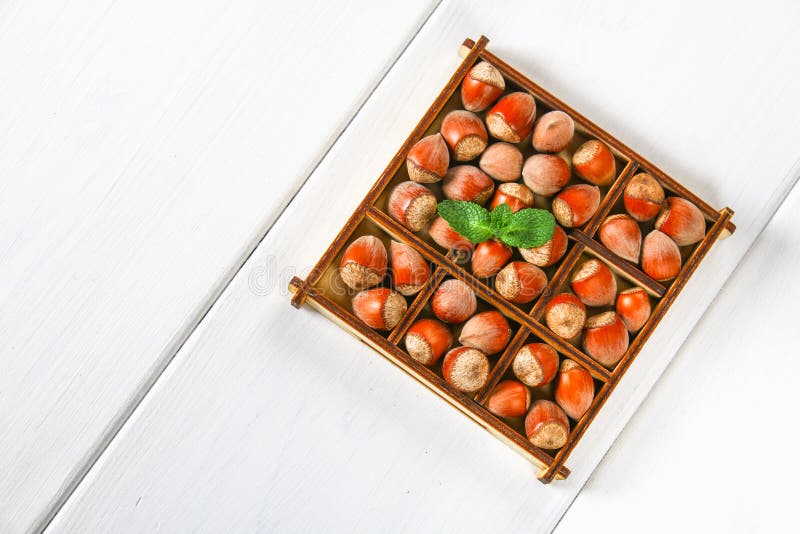 Walnut Hazelnuts in a Square Wooden Box with Dividers on a White Wooden ...