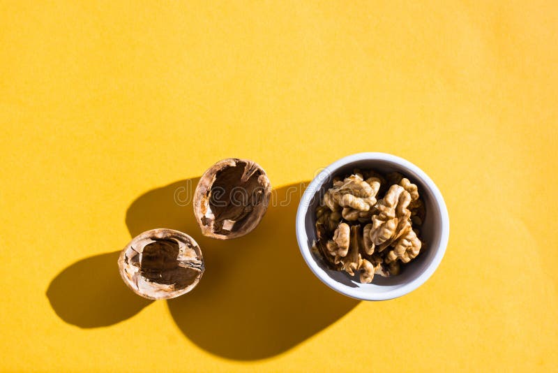 Walnut Kernels in a Bowl and Walnut Shells on a Yellow Table Stock ...