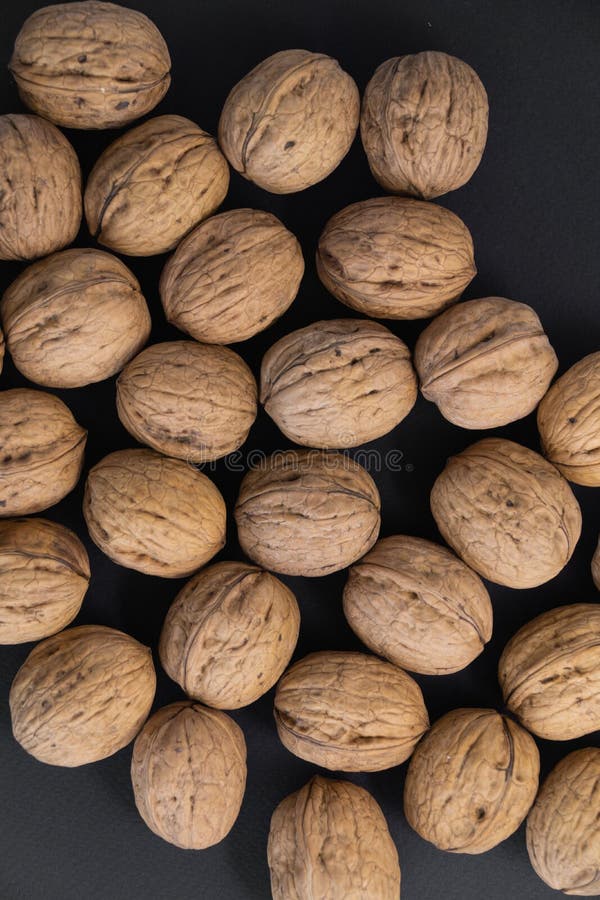 Walnuts in the Shell on Black Surface, Top View. Background of Round ...