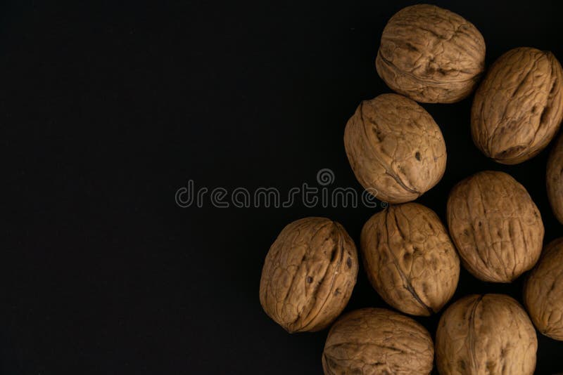 Walnuts in the Shell on Black Surface, Top View. Background of Round ...